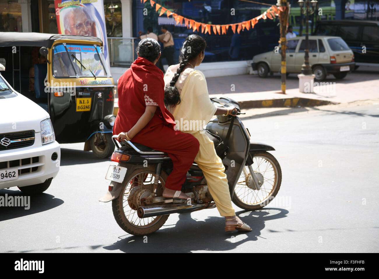 Two ladies ride on small motorbike on roads of Kottayam ; Kerala ...