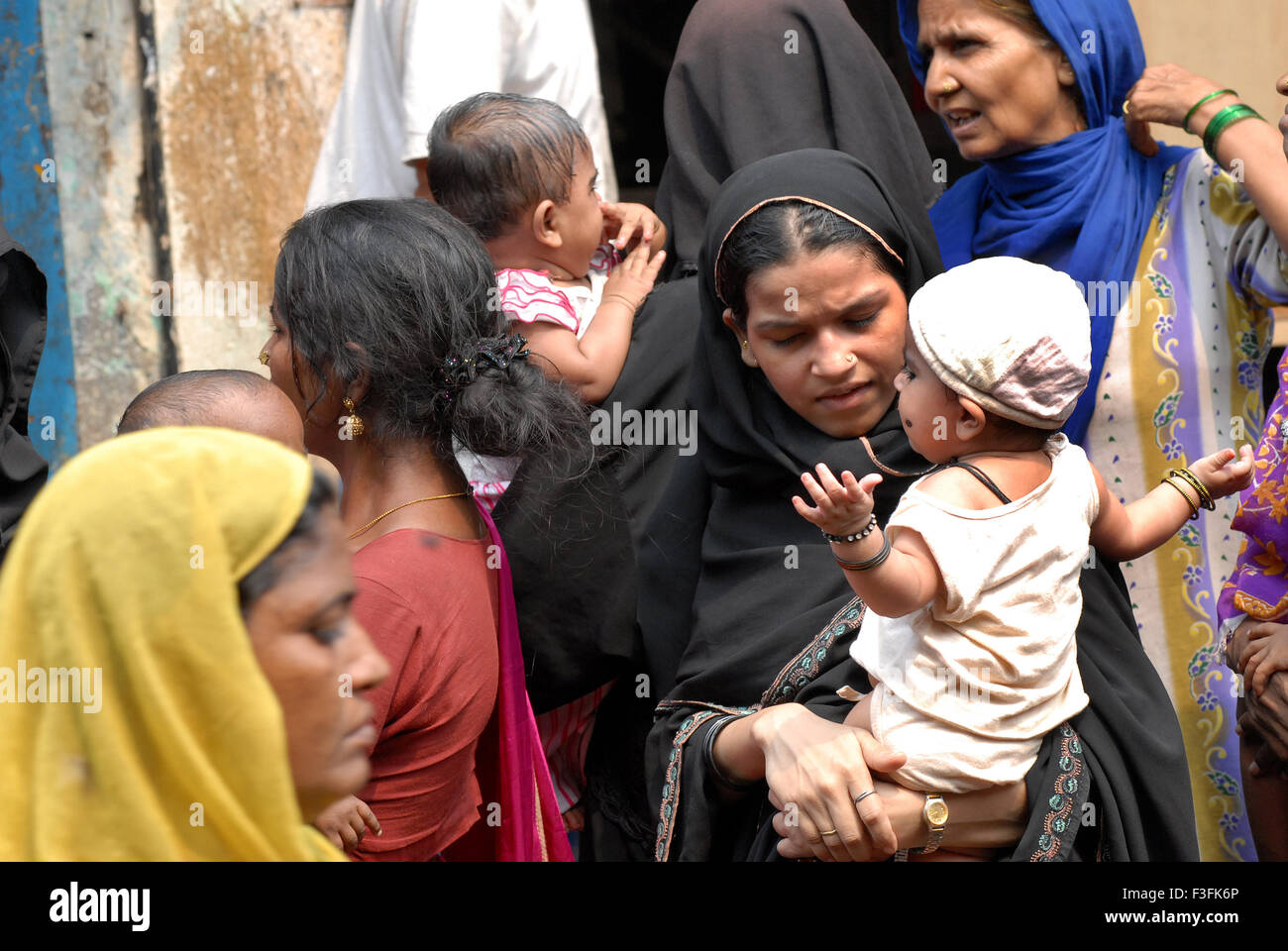 Muslim women stand in a queue with their children at a pulse polio ...