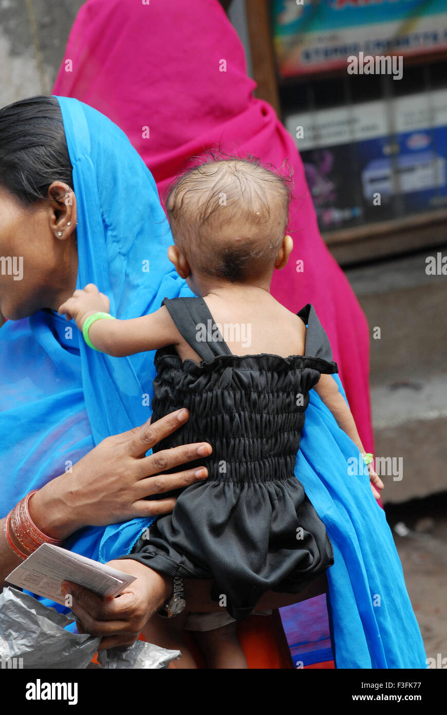Muslim women stand in a queue with their children at a pulse polio ...
