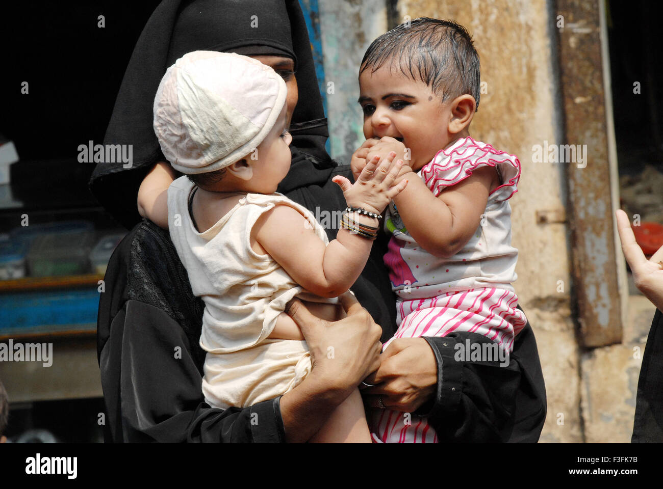 Muslim women stand in a queue with their children at a pulse polio ...