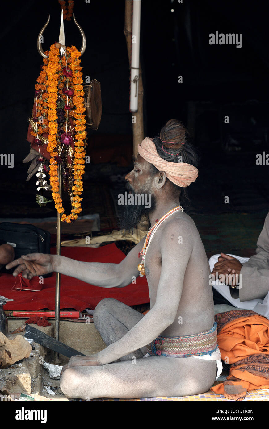 A naga sadhu from the Juna Akadha sits with his Trishul at their camp ...