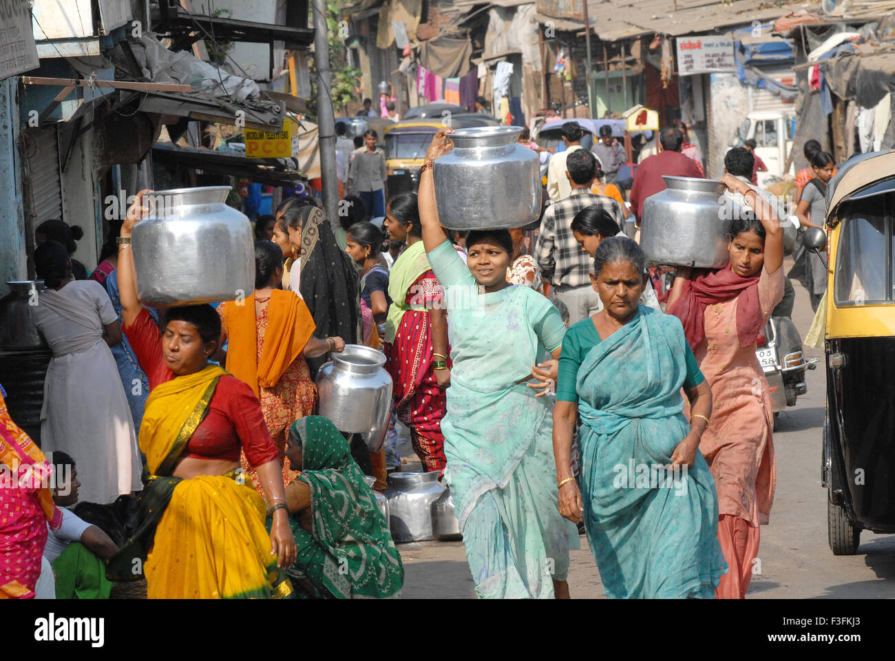 Women carry drinking water in aluminum containers on their heads at a ...