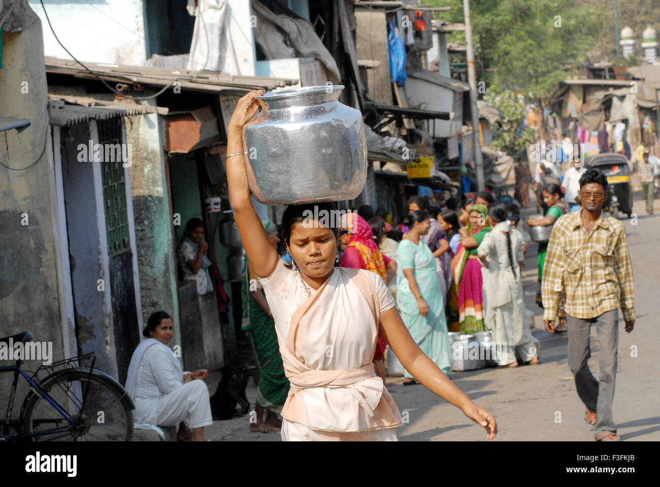 Women carry drinking water in aluminum containers on their heads at a ...