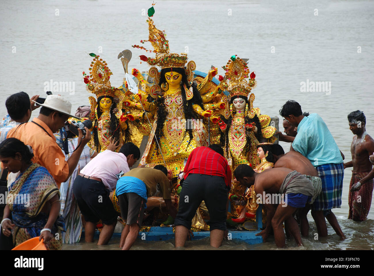 Devotees immersing Durga model in river Stock Photo - Alamy