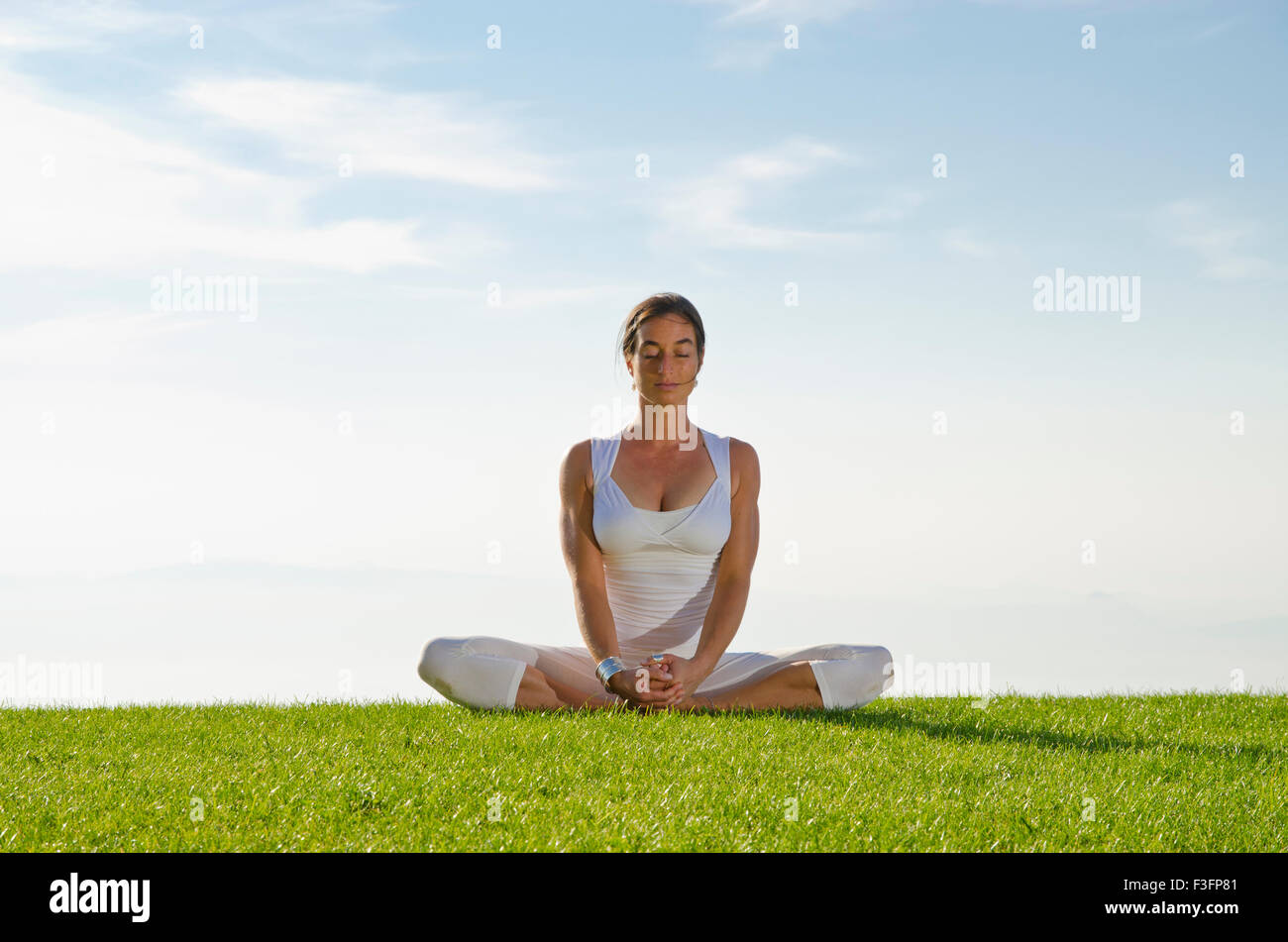 Young woman practising Hatha-Yoga outdoor, showing the pose bhadrasana ...