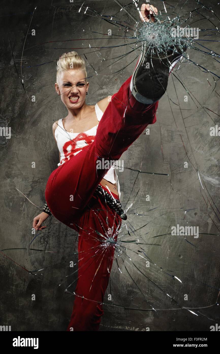 Punk girl breaking glass with her boot Stock Photo - Alamy