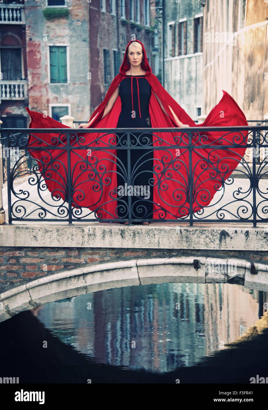 Beautiful woman in red cloak on a bridge Stock Photo - Alamy