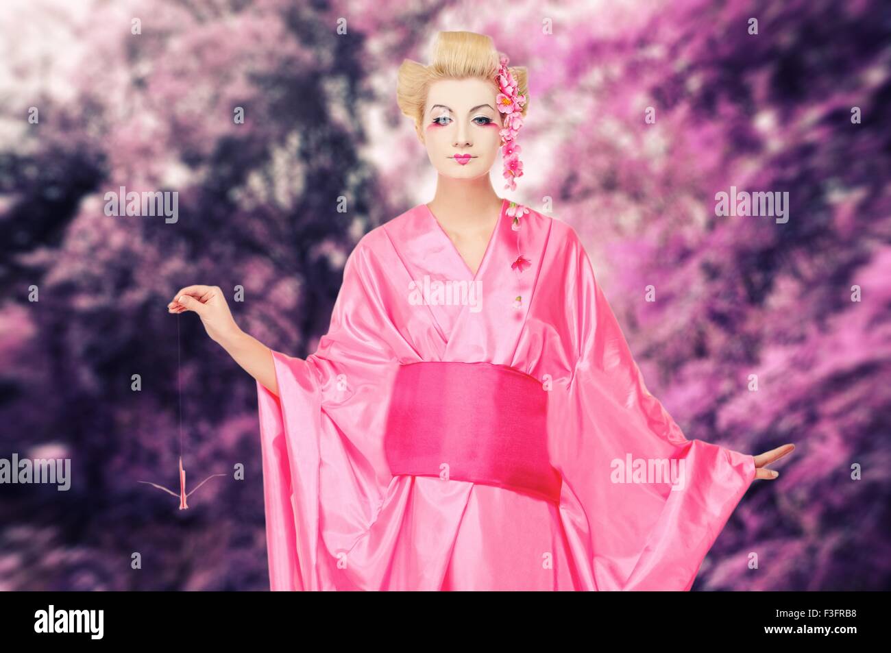 Geisha holding origami bird over blurred background Stock Photo - Alamy