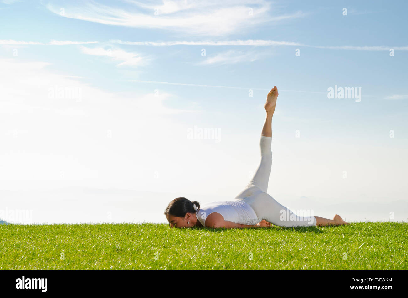 Young woman practising Hatha-Yoga outdoor, showing the pose ardha ...