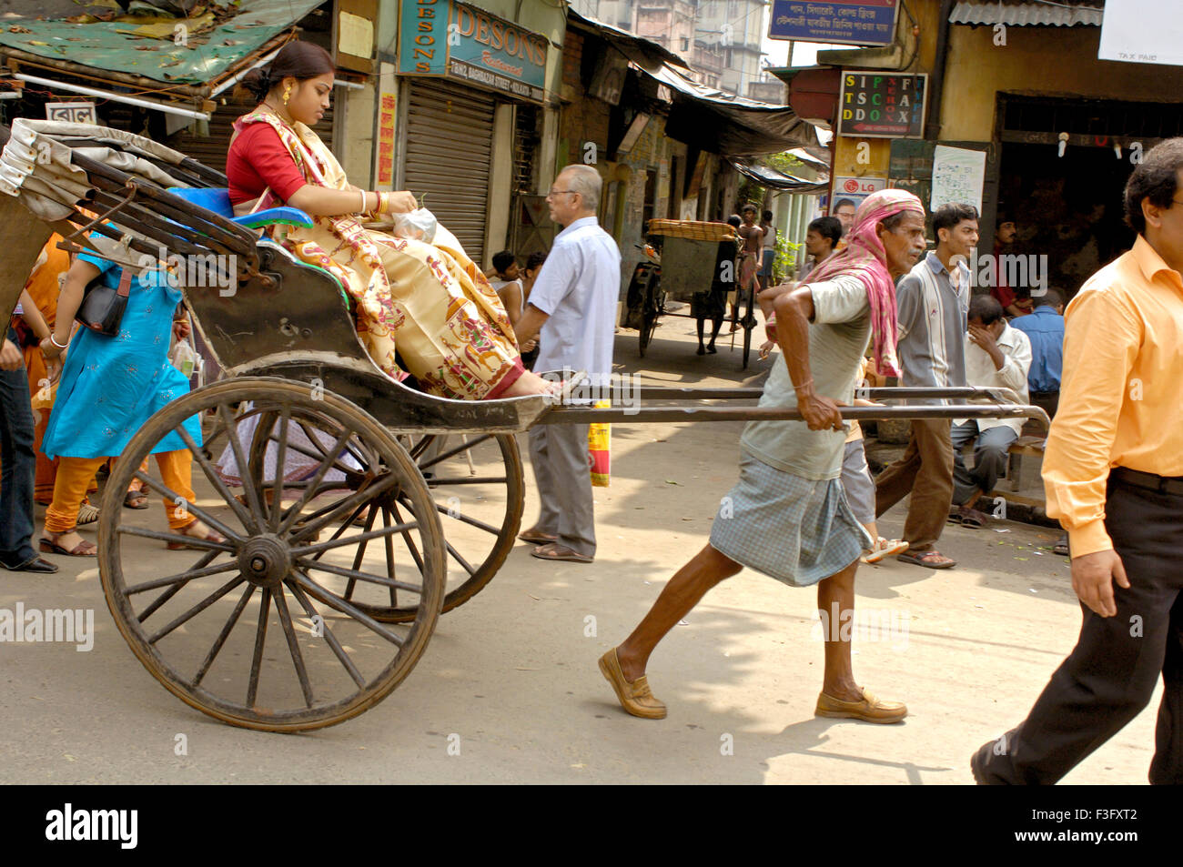 hand rickshaw puller pulling rickshaw with woman passenger on street of ...