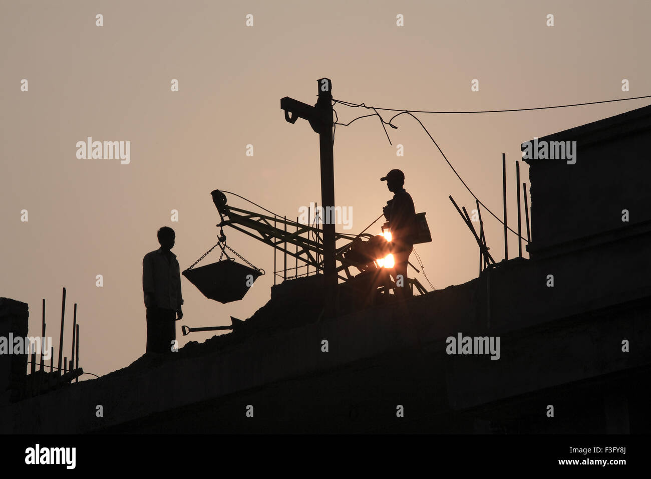 Workers doing construction work against setting sun Stock Photo - Alamy