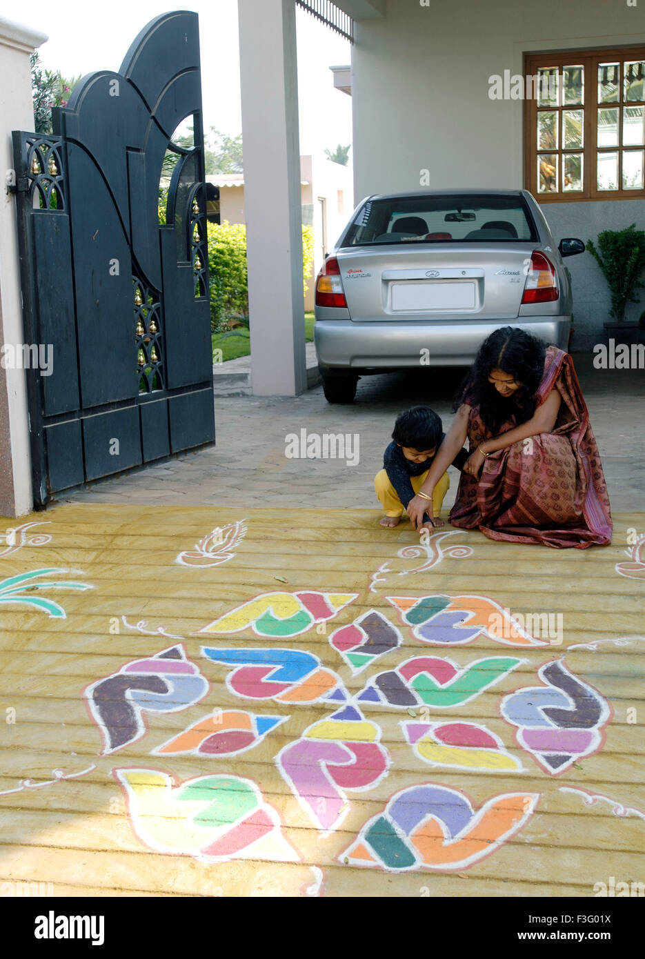 Woman making kolam or rangoli in front of house ; Pongal festival ...