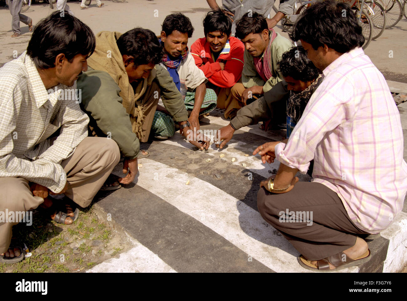 Workers playing sola goti game on road at New Coch Behar railway ...