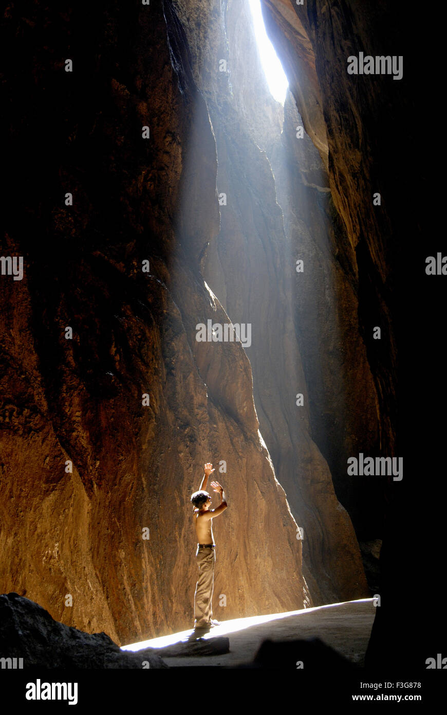 Sun rays falling on young man through rock crevice at Yanna forest ...