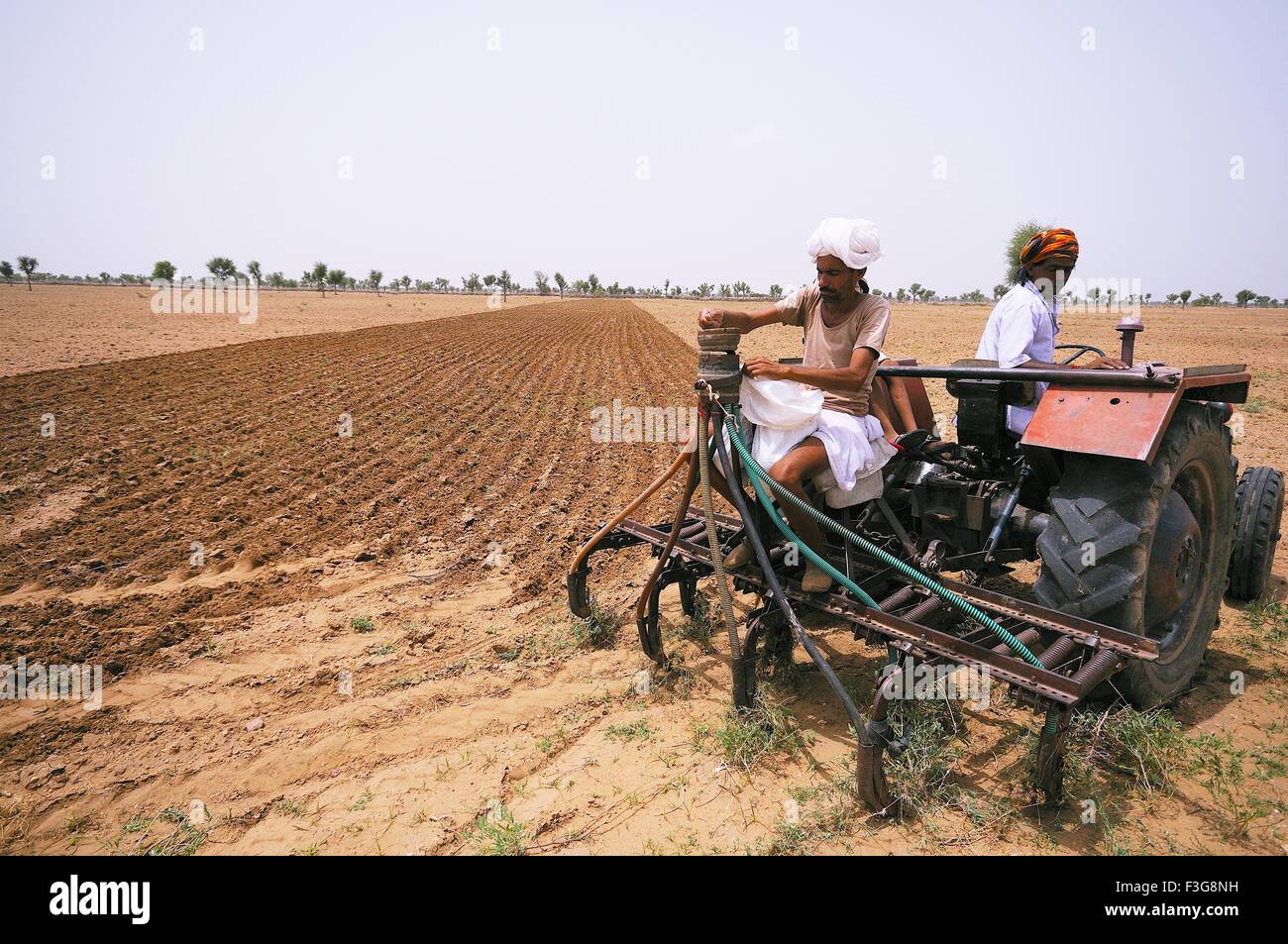 Farmers ploughing field with tractor ; Jajiwal ; Jodhpur ; Rajasthan ...