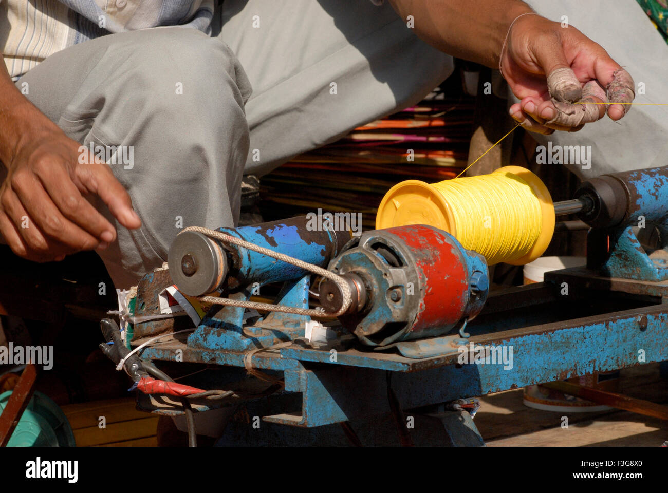 Shop of kites ; man filling reel of manja with help of machine ; Makara ...