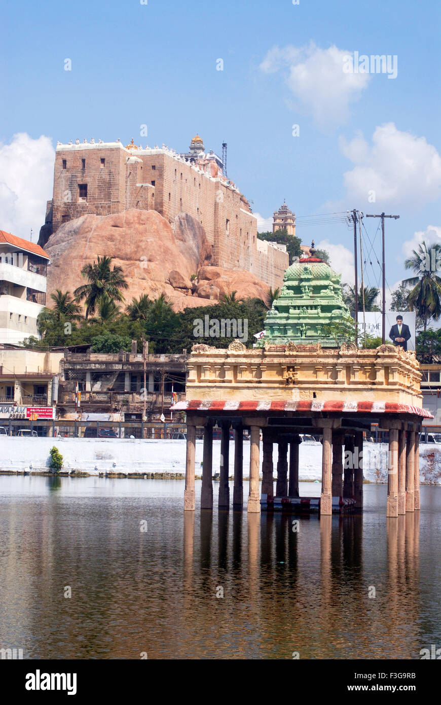 Rock fort with holy tank and pavilion surrounded by buildings and shops ...