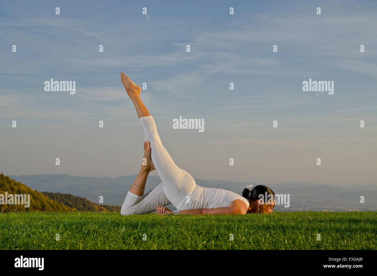 Young woman practising Hatha-Yoga outdoor, showing the pose ardha ...