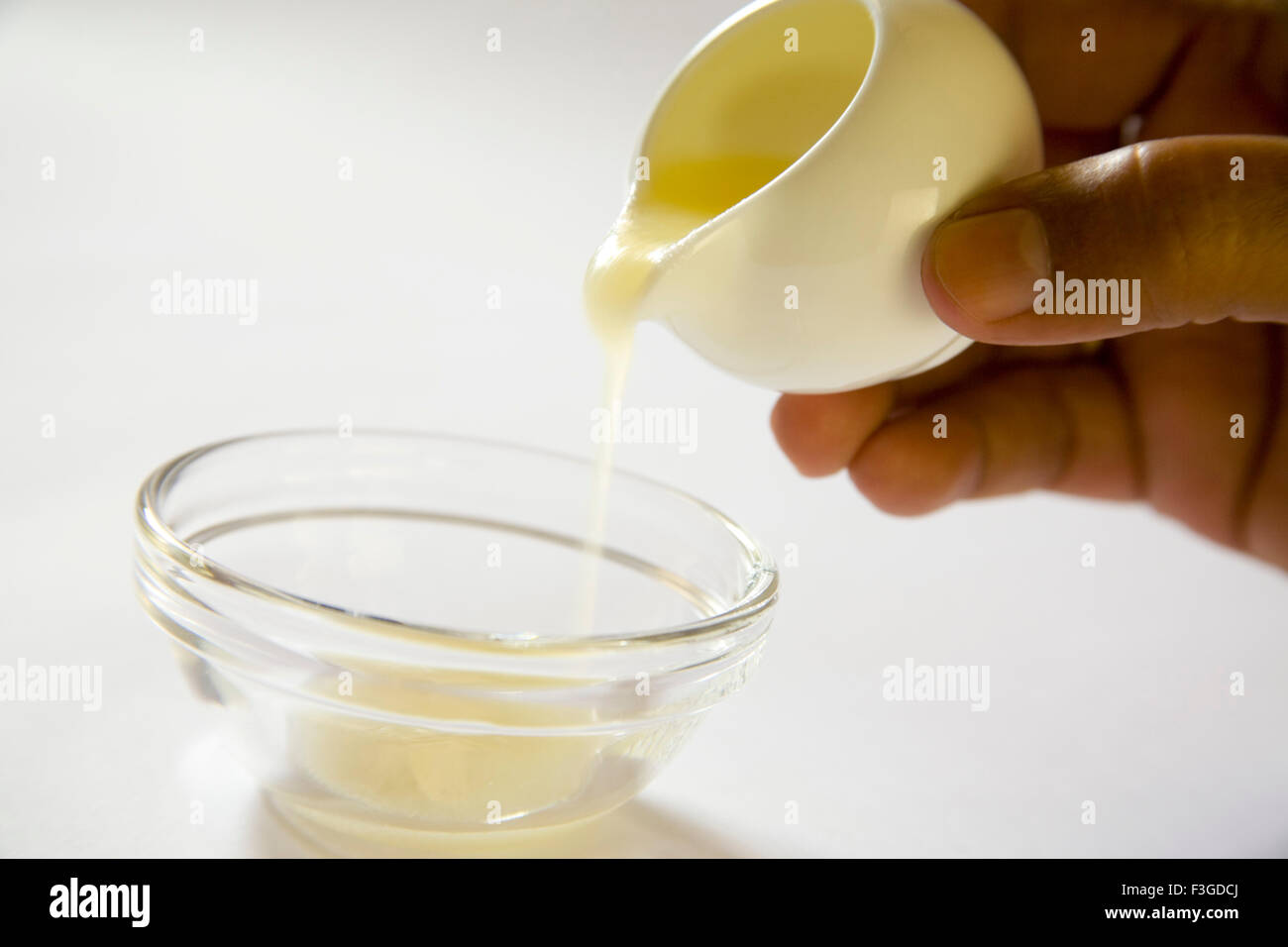 Hand pouring homemade ghee or dairy product in bowls Stock Photo - Alamy