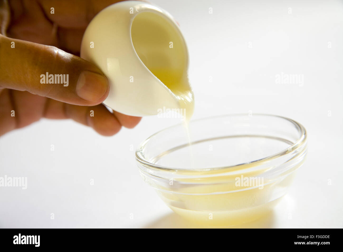 Hand pouring homemade ghee or dairy product in bowls Stock Photo - Alamy