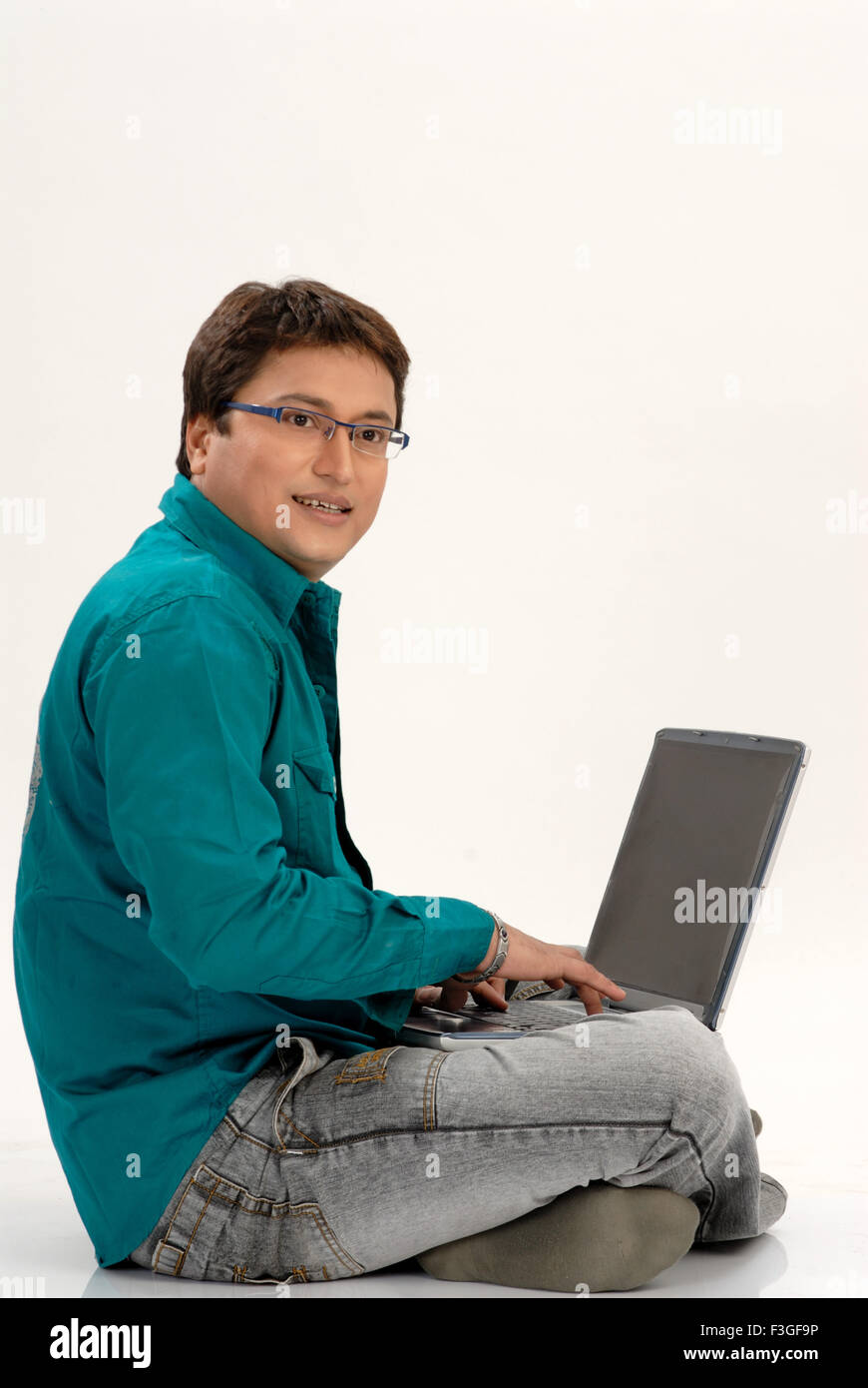 Indian man sitting working on laptop computer white background - MR ...