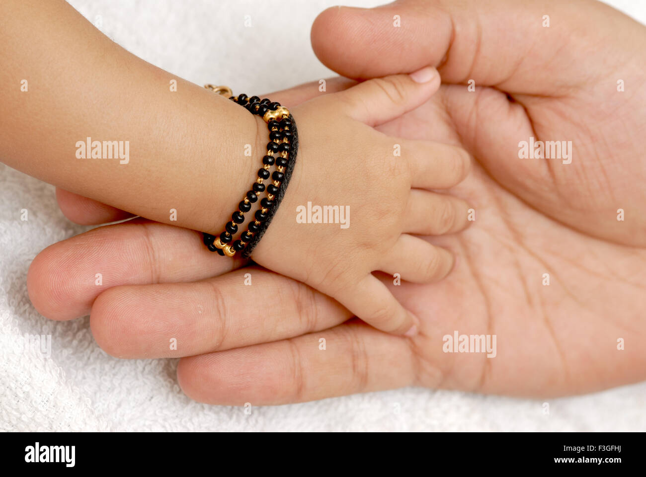 Indian son baby child hand with amulet touching feeling hand of father ...