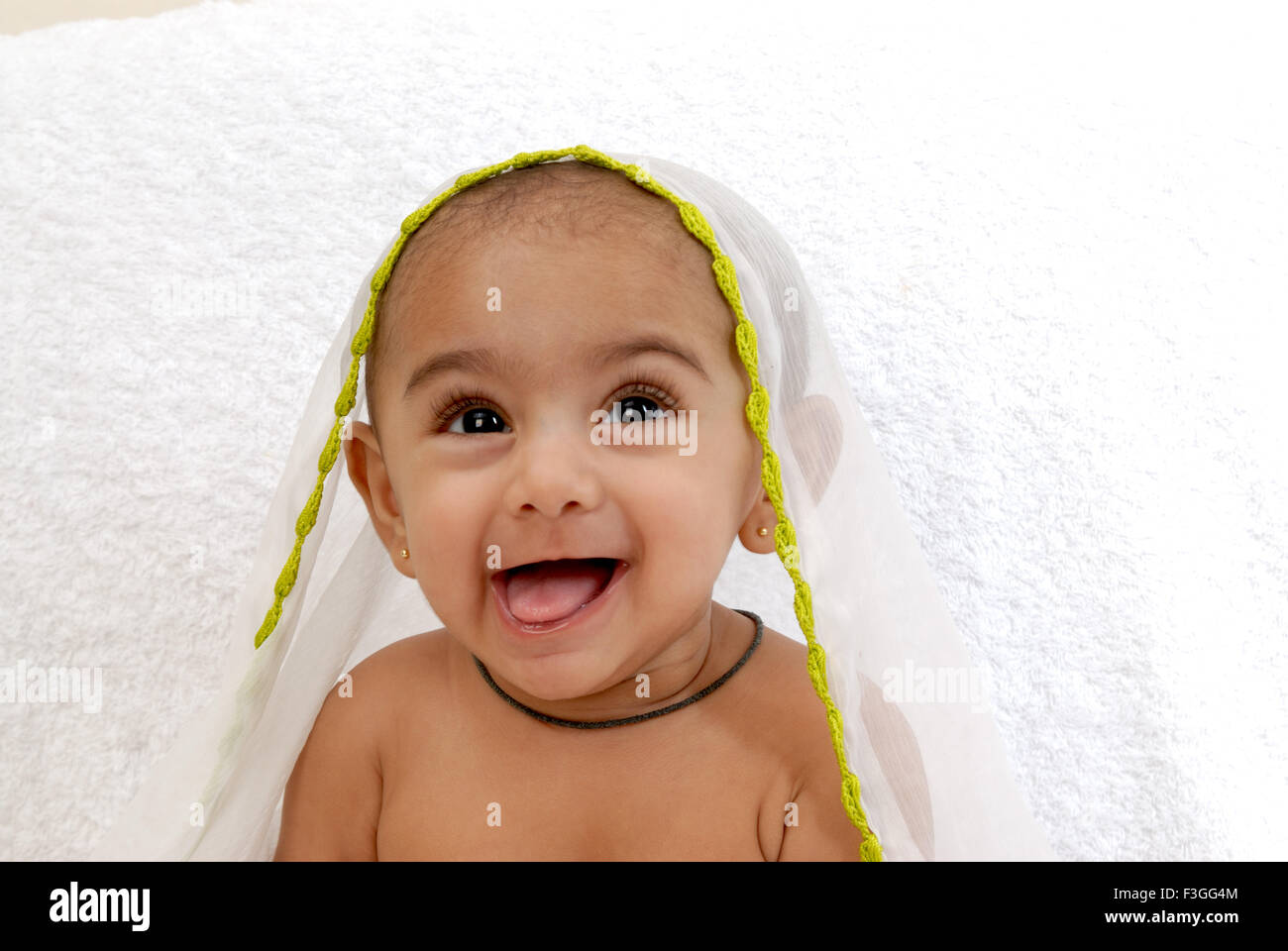 Baby looking up , laughing , wearing amulet in neck , ear studs , white ...