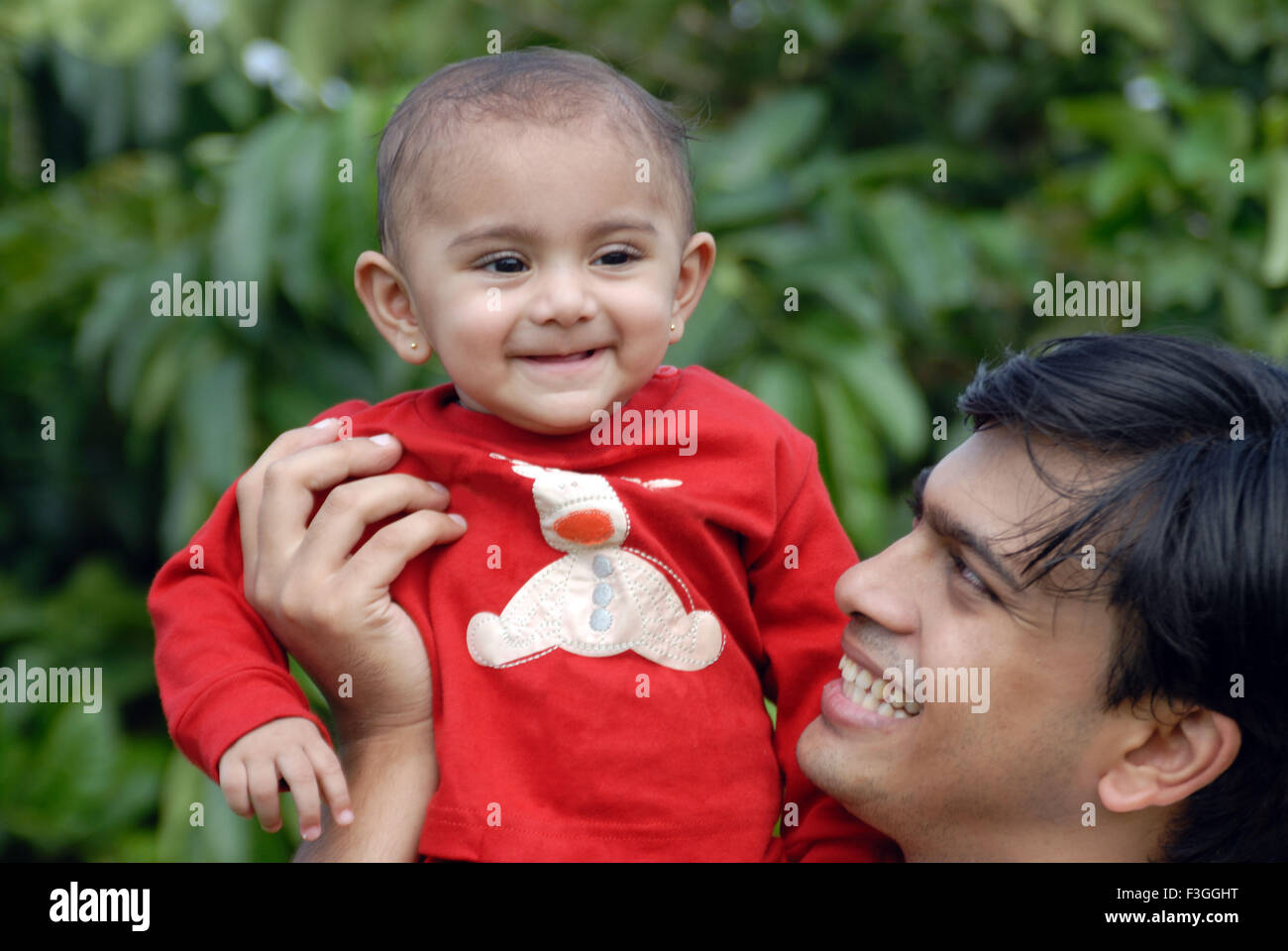 South Asian Indian baby playing with her father in the garden ; India ...