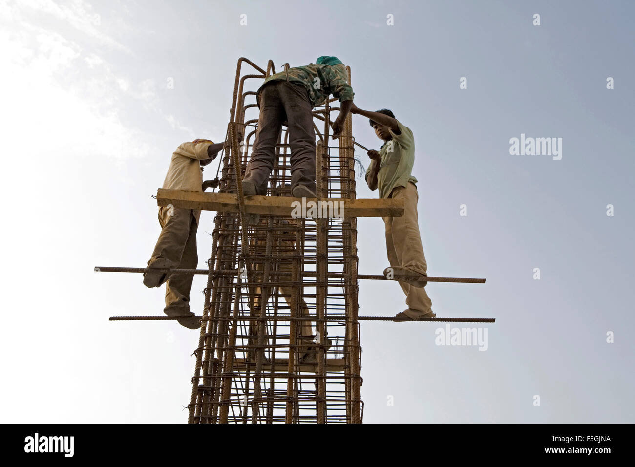 Workers standing precariously without safety belts nor helmets and ...
