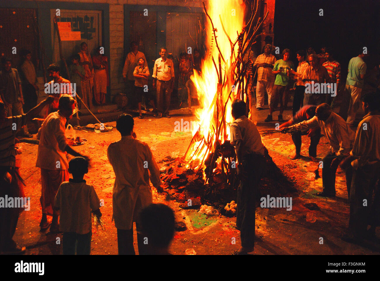 Holi festival ; people baking plant of wheat in the fire of Holika ...