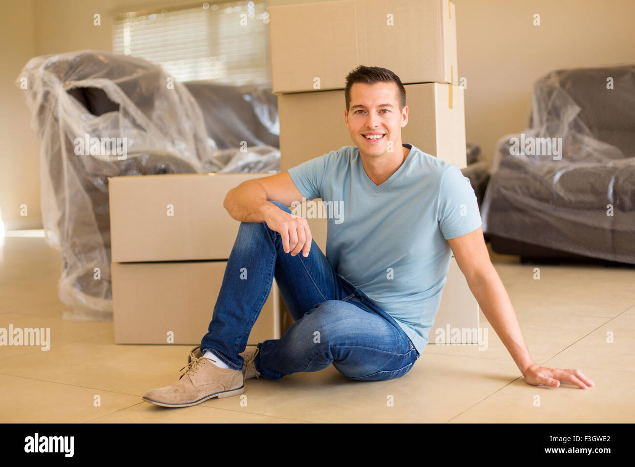relaxed young man sitting on floor in new home Stock Photo - Alamy