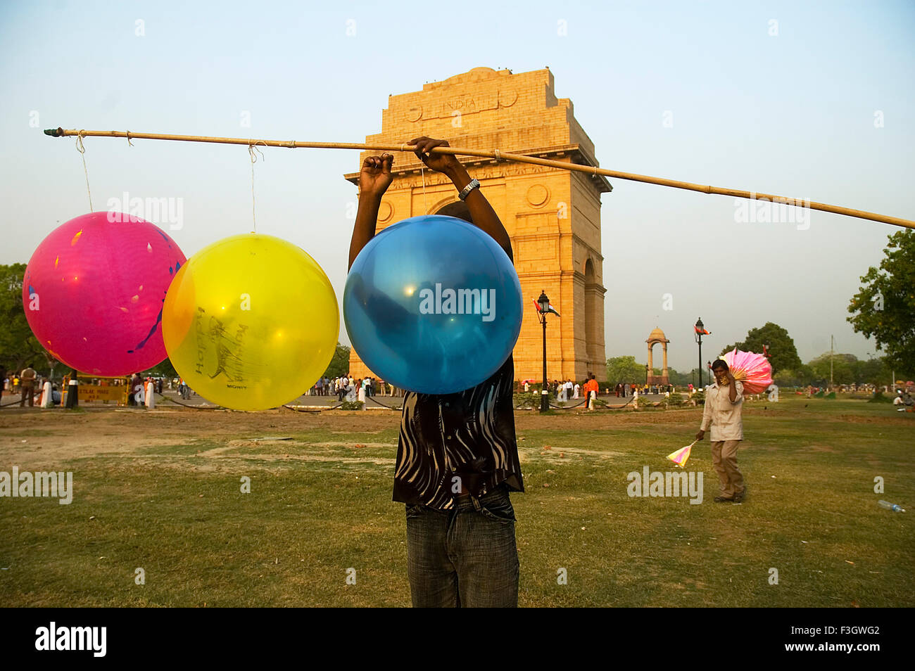 Balloon seller hangs balloons on long stick at India Gate ; New Delhi ...