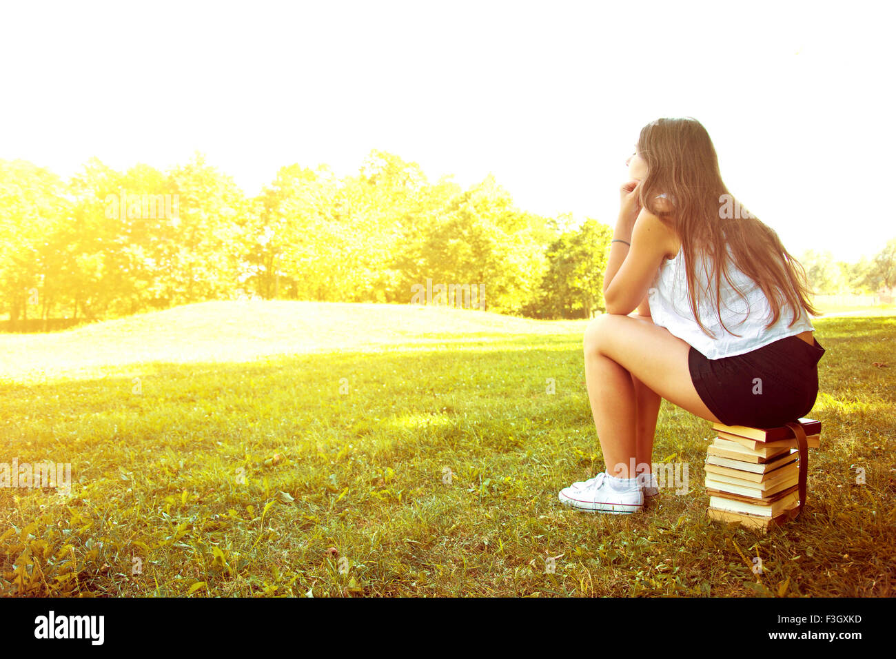 Attractive female college student daydreaming and sitting on the stack ...