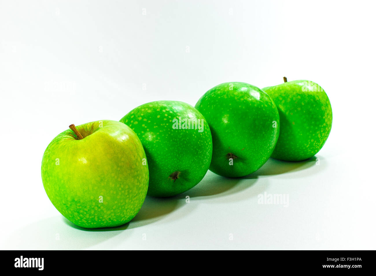 four green apples on white background Stock Photo - Alamy