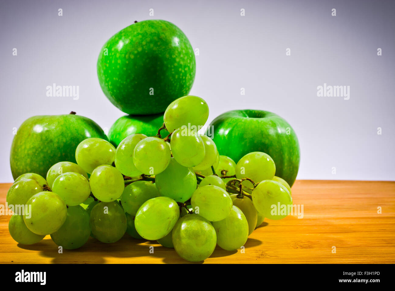 four green apples and grapes on white background Stock Photo - Alamy