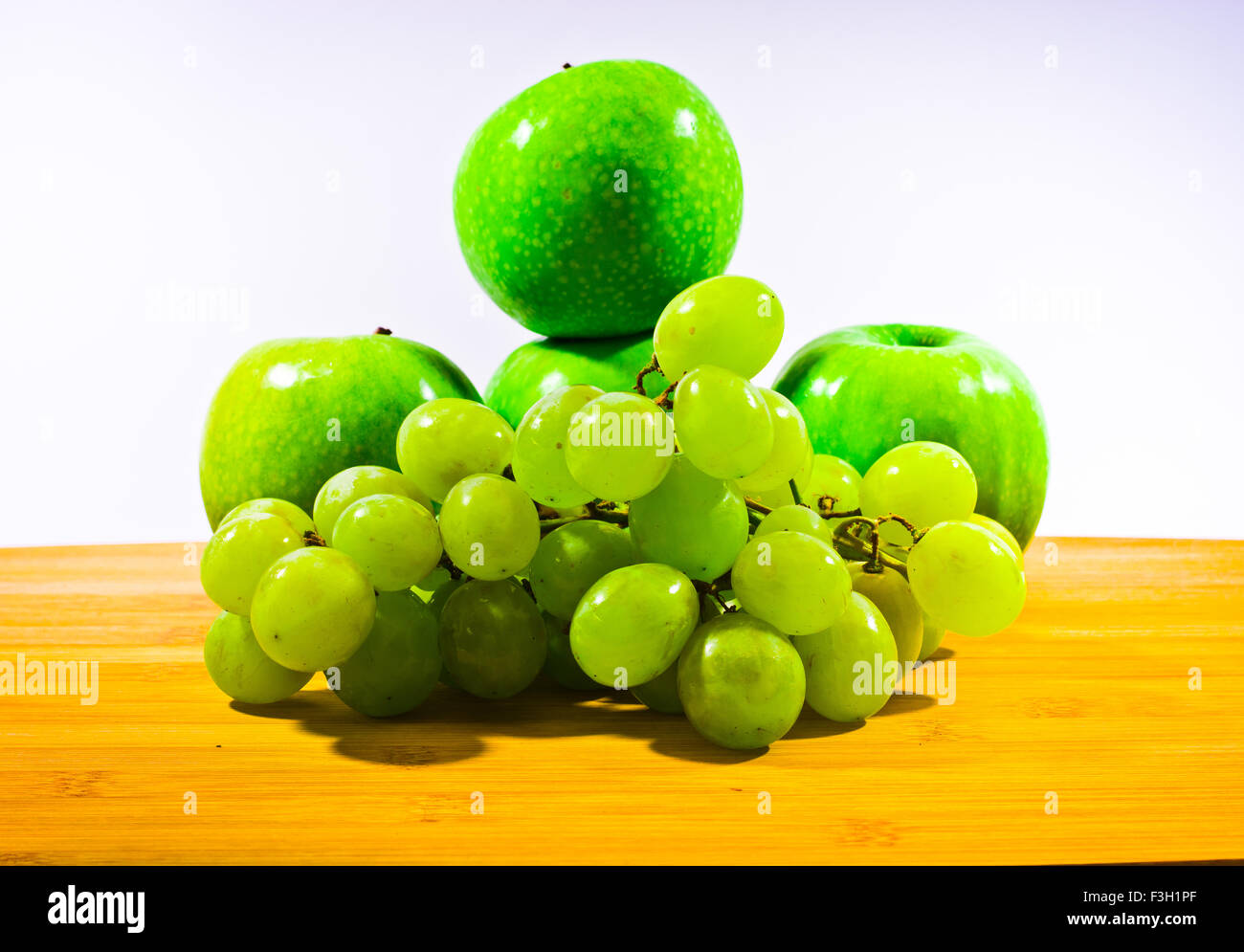 four green apples and grapes on white background Stock Photo - Alamy