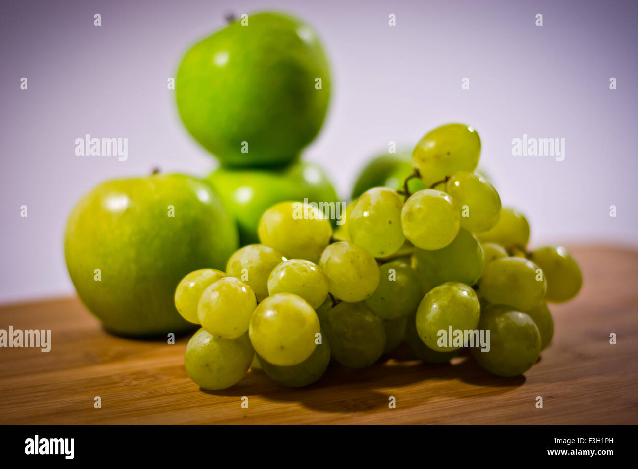 four green apples and grapes on white background Stock Photo - Alamy