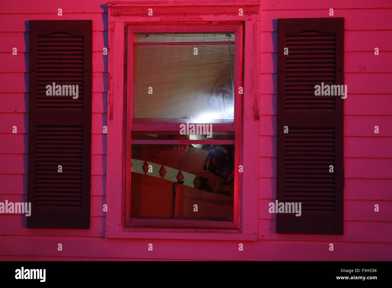 A firefighter is seen through a window looking for the source of a ...