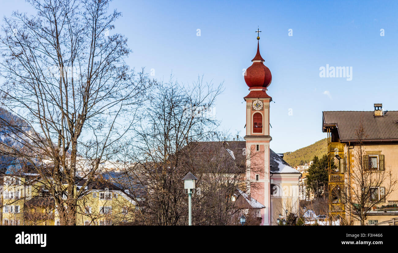 Snowy alpine village in Italy illuminated by sun with mountains in the ...