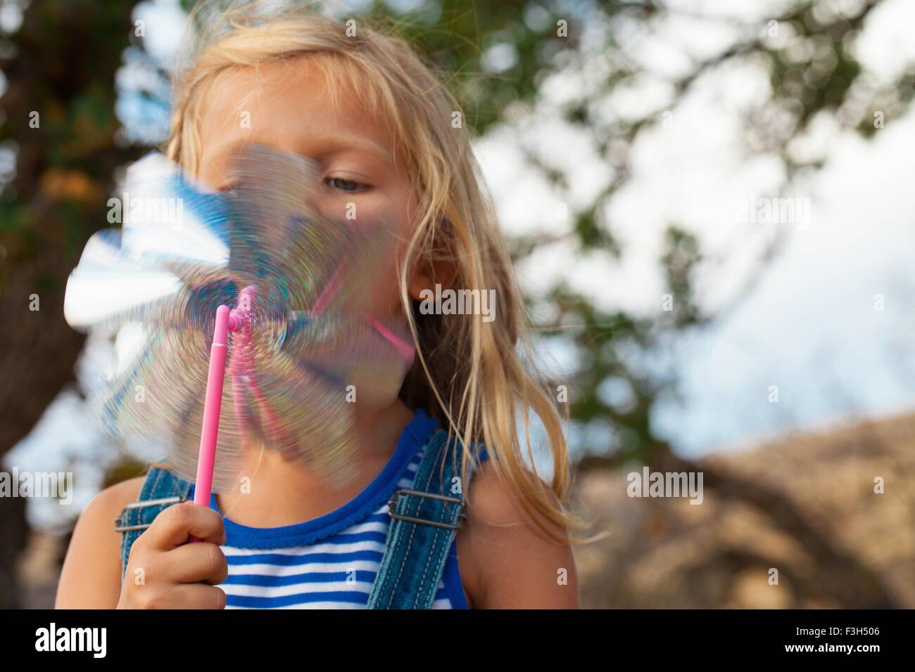 Girl blowing pinwheel Stock Photo - Alamy