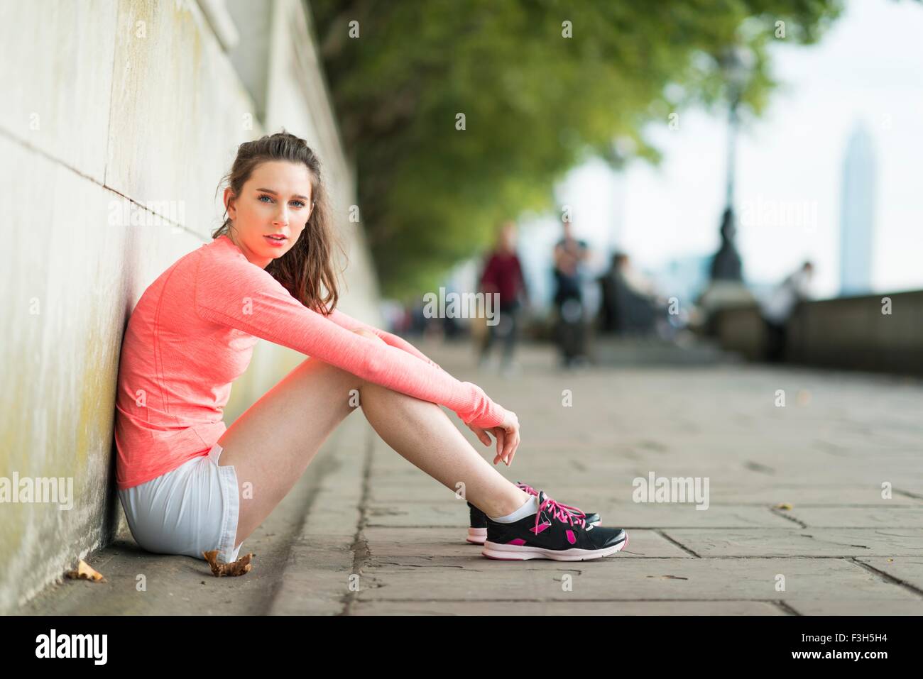 Portrait of young female runner sitting along riverside Stock Photo - Alamy