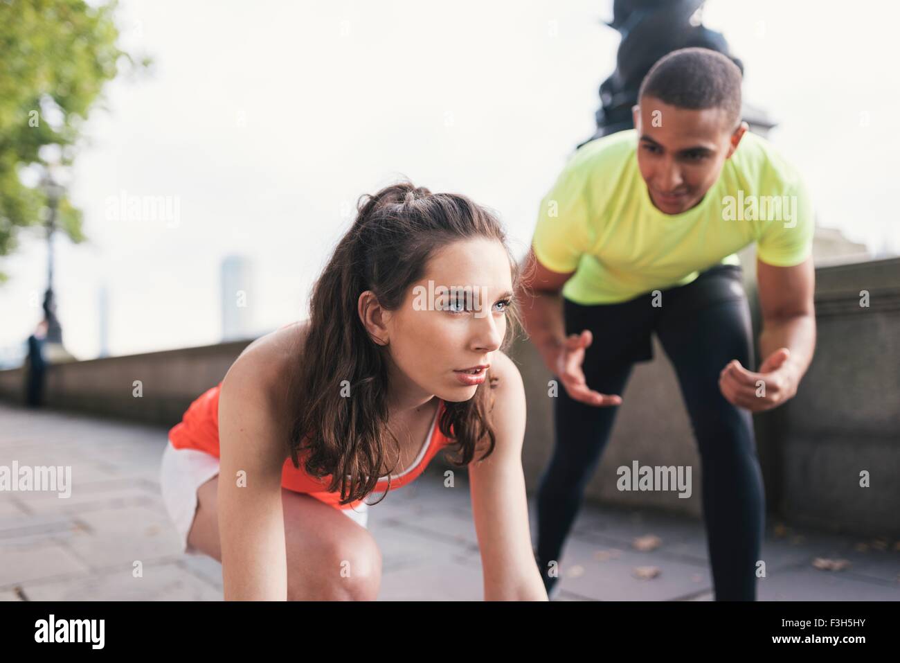 Young male trainer encouraging female runner on riverbank Stock Photo ...