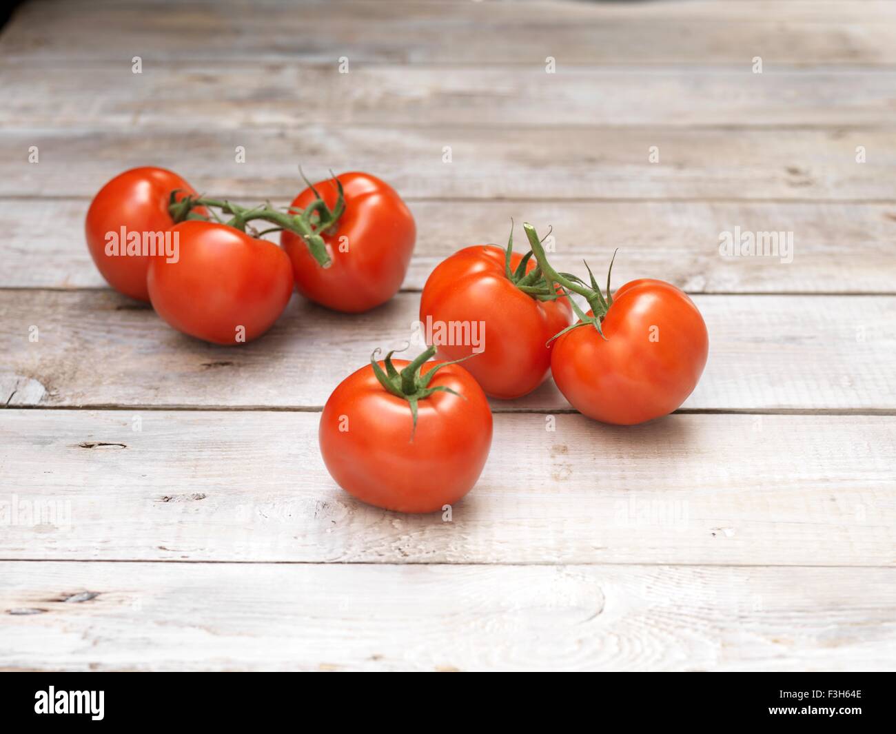 Six red vine tomatoes on wooden table Stock Photo - Alamy