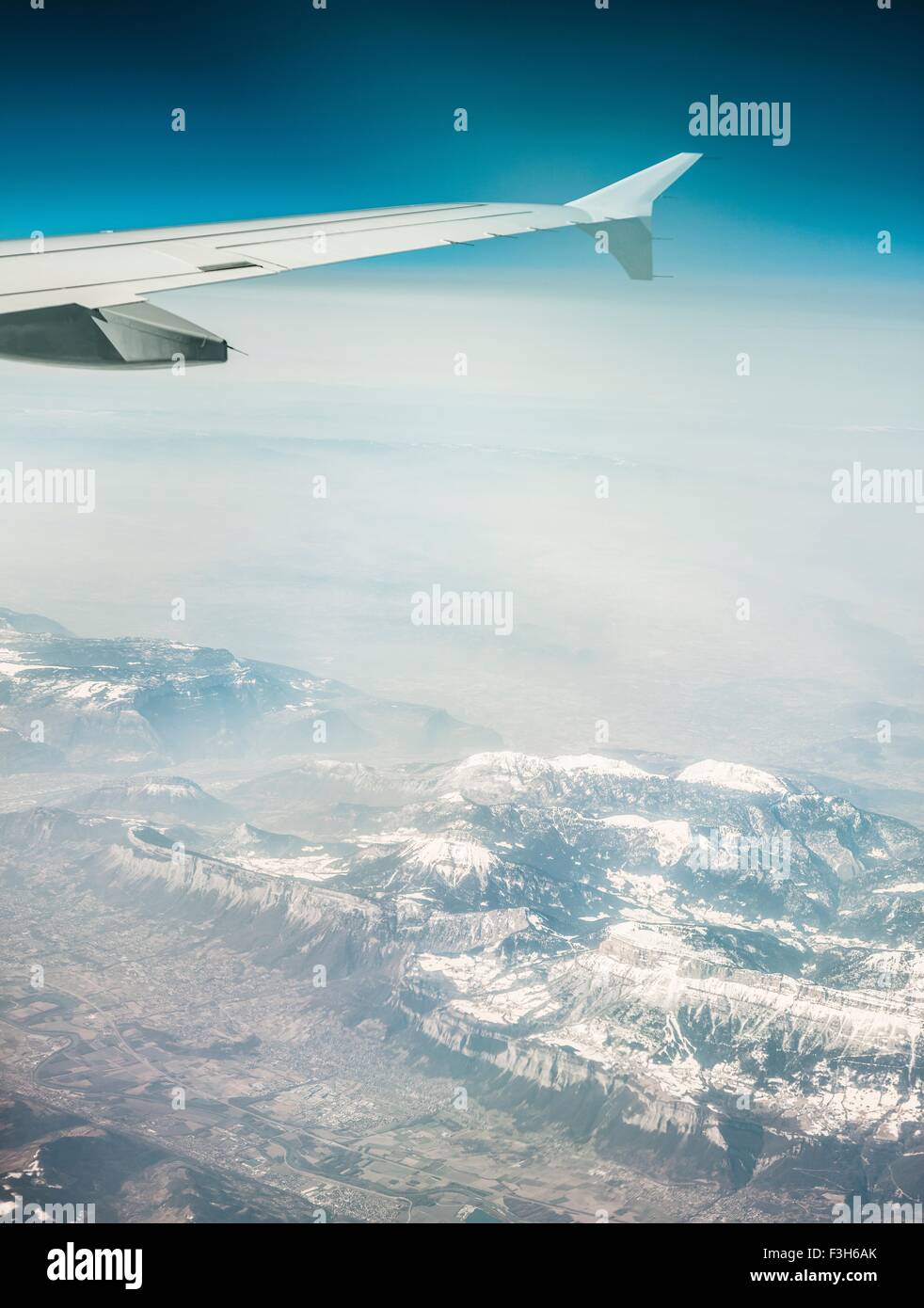 Aerial view of airplane wing and misty snow capped mountains Stock Photo - Alamy