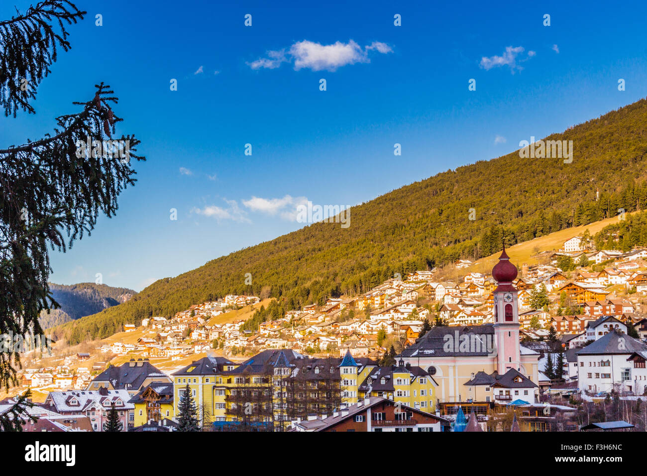 Snowy alpine village in Italy illuminated by sun with mountains in the ...