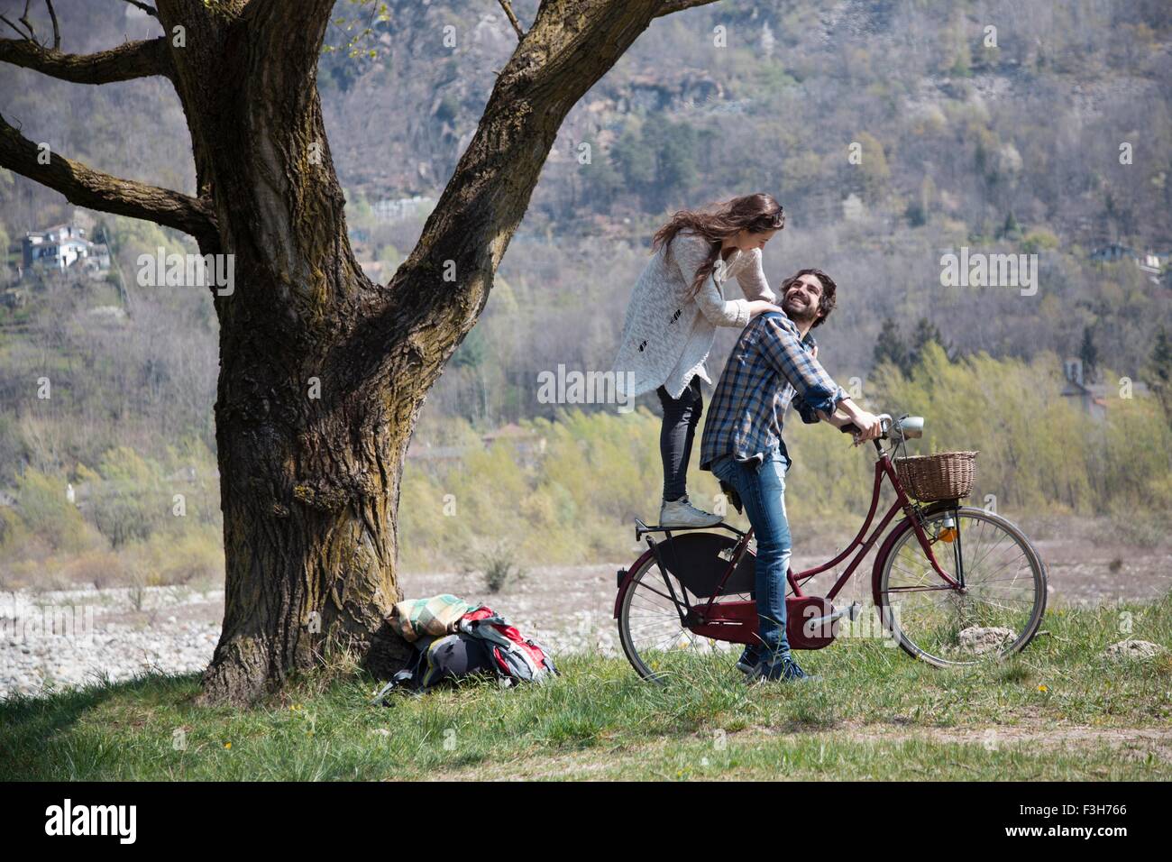 Young woman standing on bicycle behind boyfriend Stock Photo - Alamy