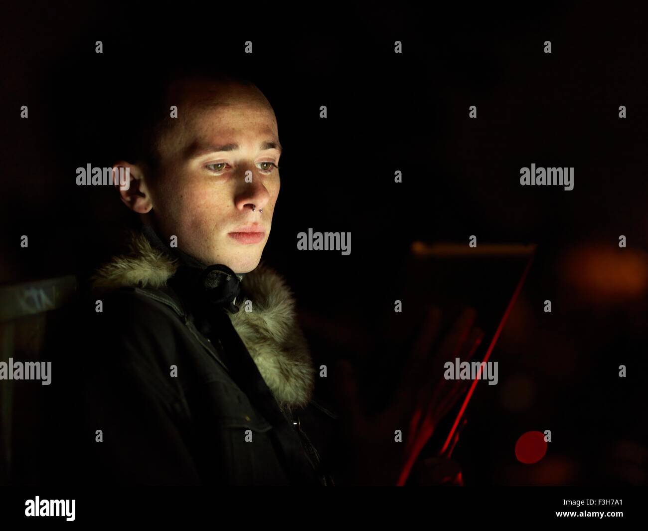 Young man sitting outdoors at night, face illuminated Stock Photo - Alamy