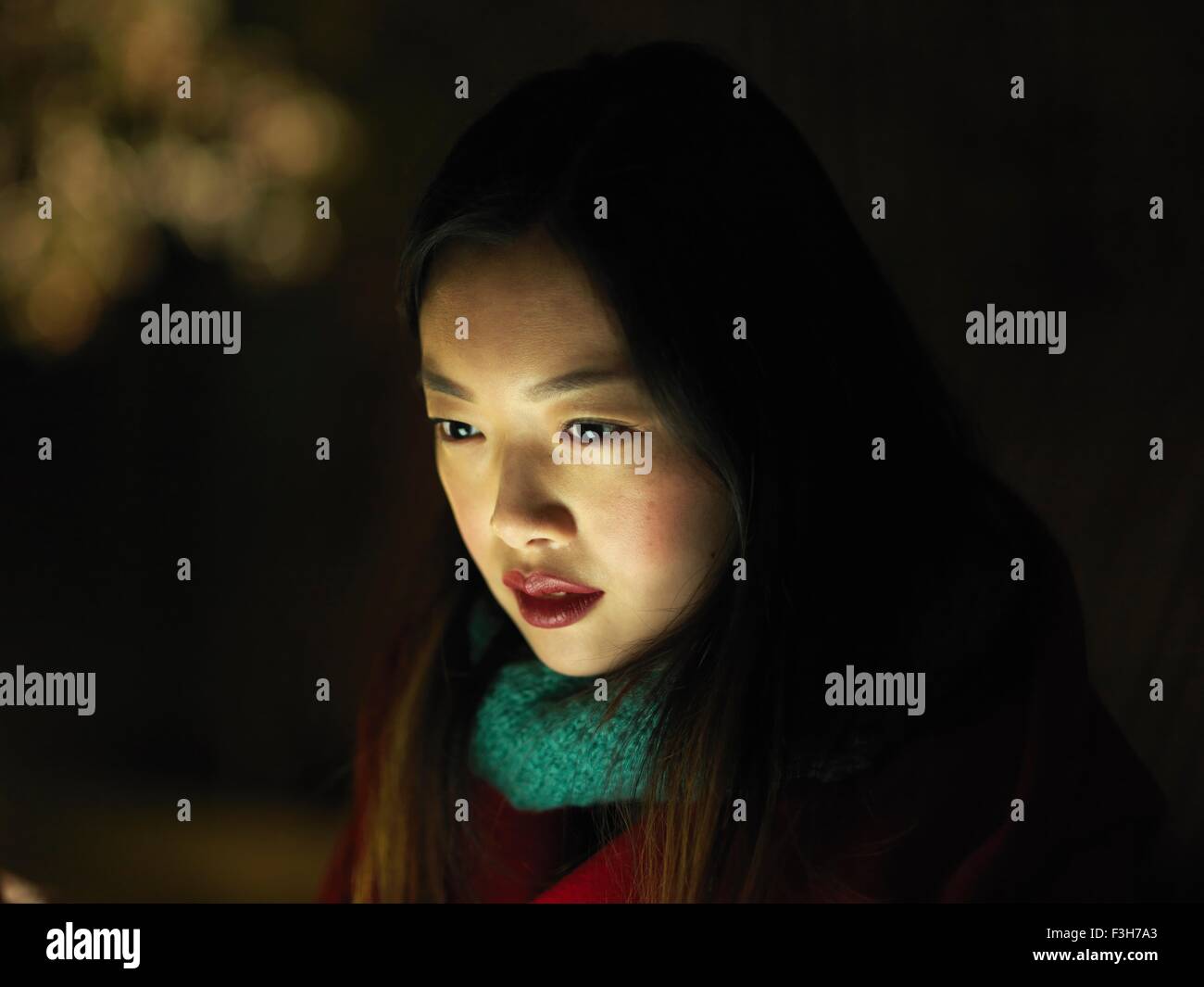 Young woman outdoors at night, face illuminated Stock Photo - Alamy