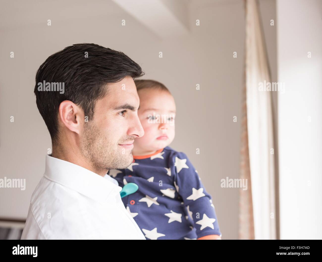 Father and young son looking out of window Stock Photo - Alamy