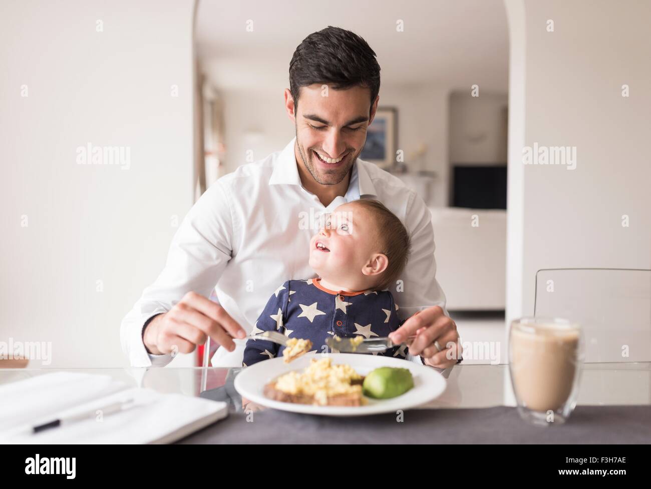 Father eating meal with young son sitting on his lap Stock Photo - Alamy